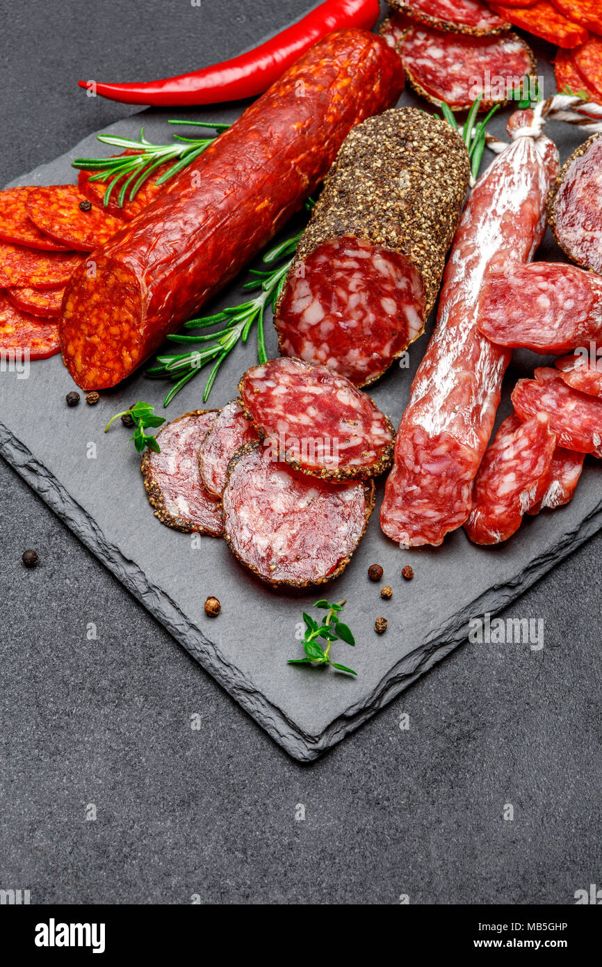 Various types of Dried organic salami sausage on stone serving board ...