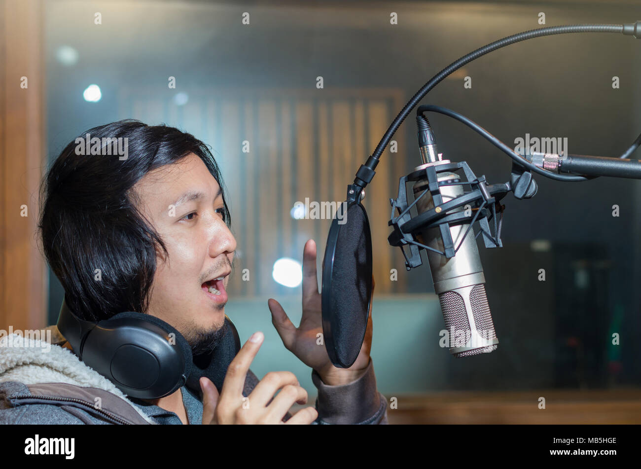 Young Asian singer recording a song with microphone in music studio ...