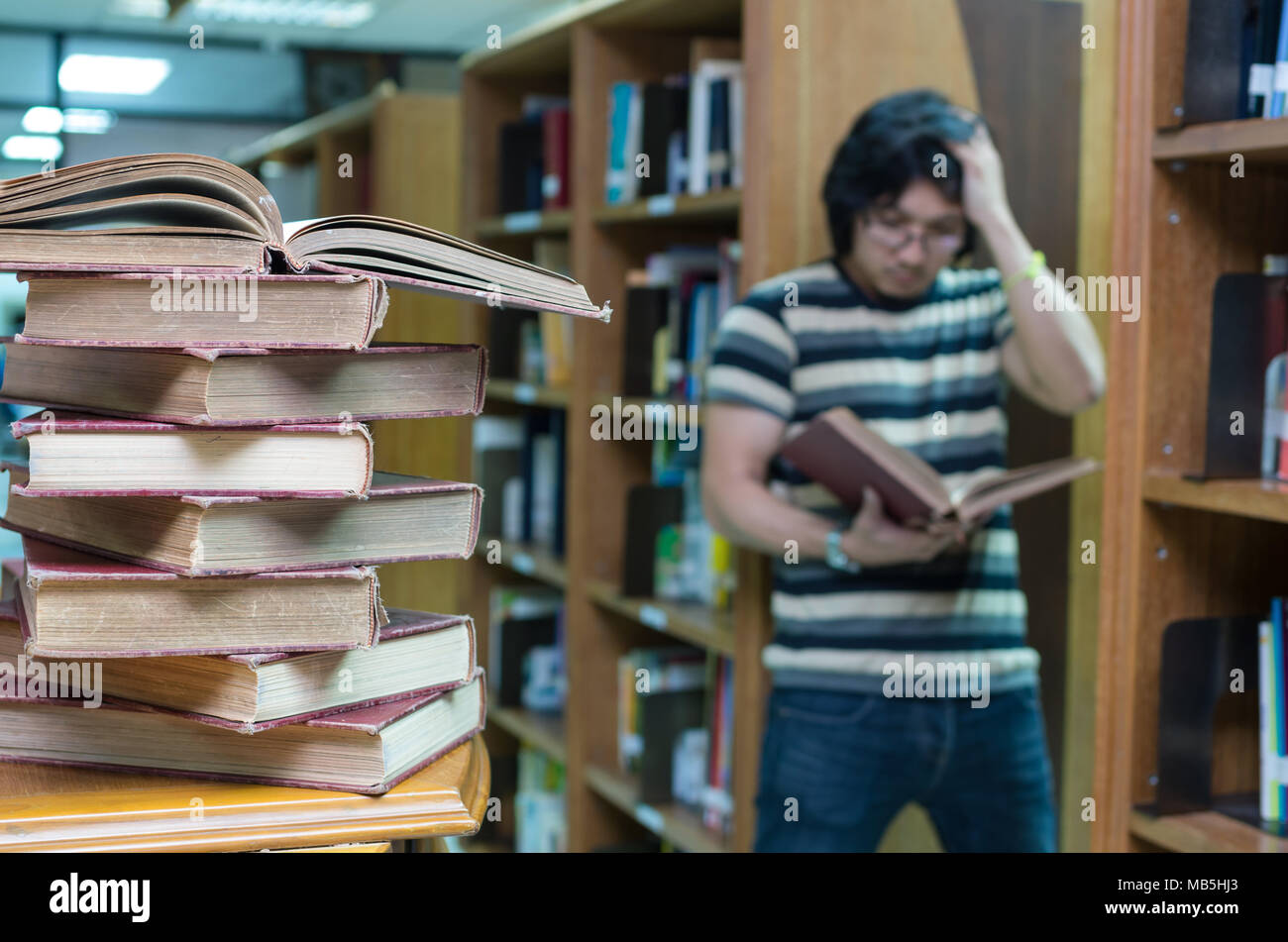 stack of old book on the desk in library with the man reading over the ...
