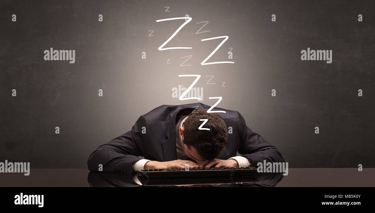 Young businessman fell asleep at the table on his keyboard concept ...