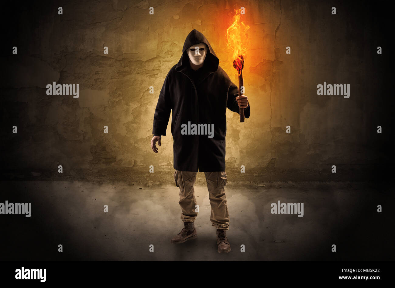 Ugly wayfarer with burning torch in his hand in front of a crumbly wall ...
