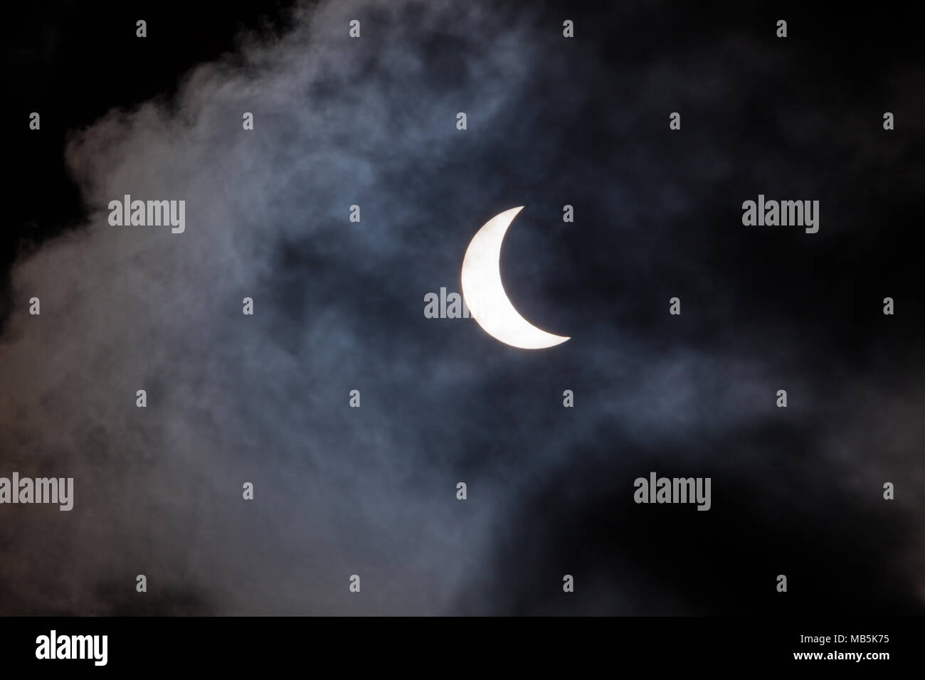Partial solar eclipse through clouds Stock Photo - Alamy