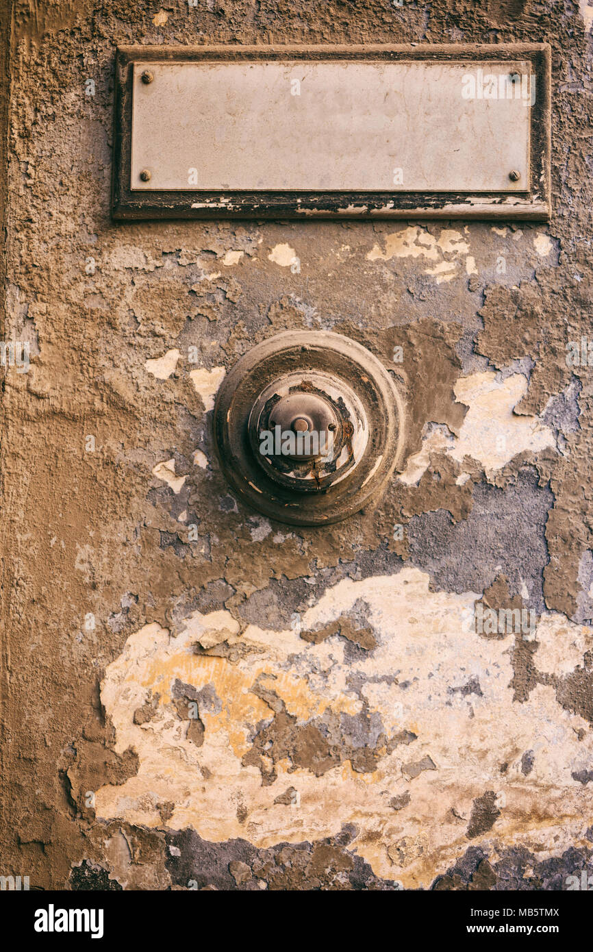 Weathered door bell and blank name label on damaged wall background ...