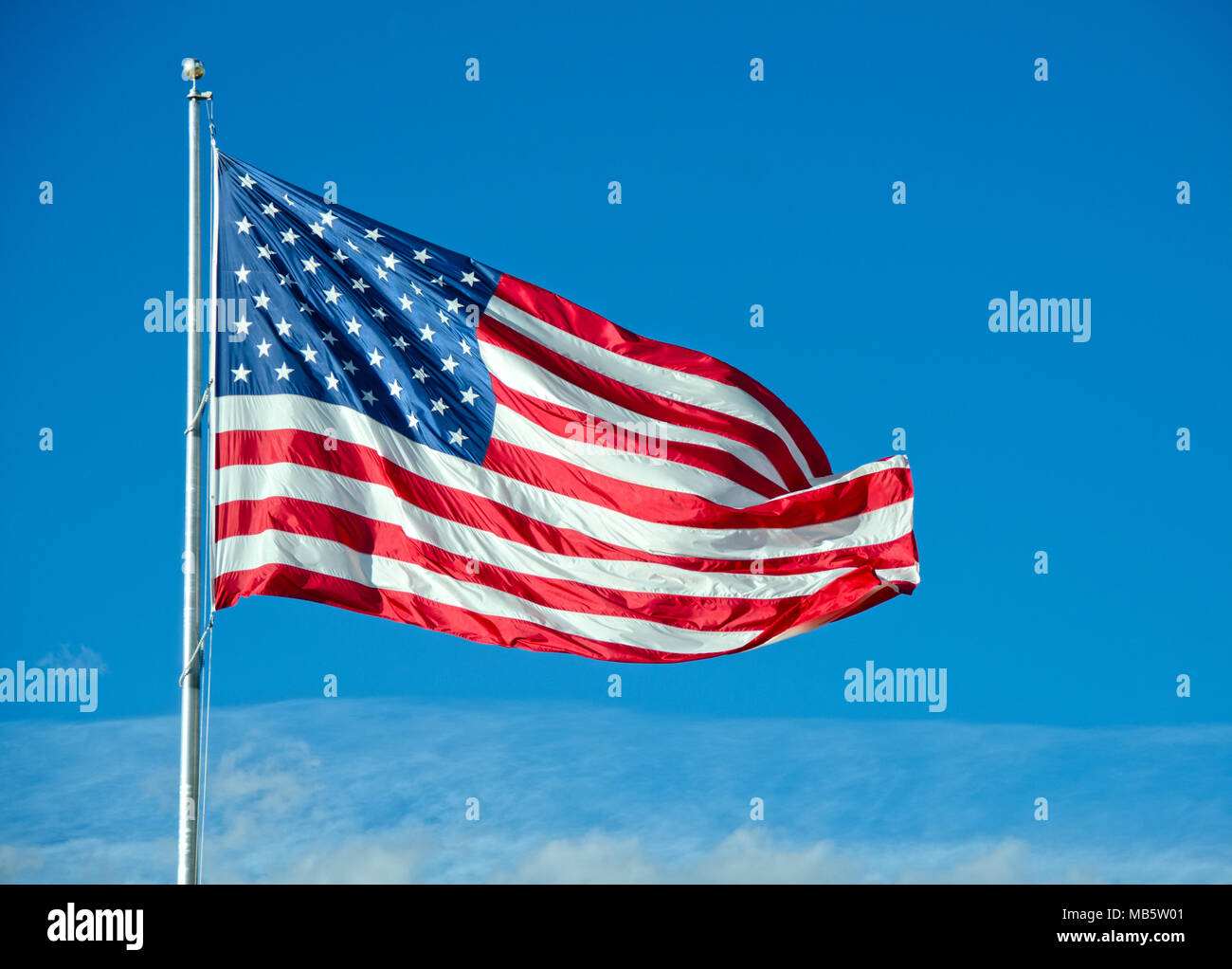 A very large American flag flies above the clouds on a beauty sunny ...