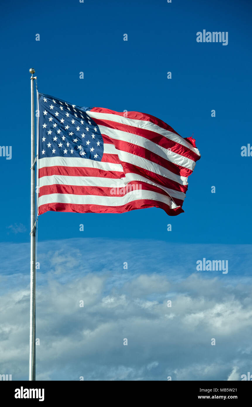 A very large American flag flies above the clouds on a beauty sunny ...