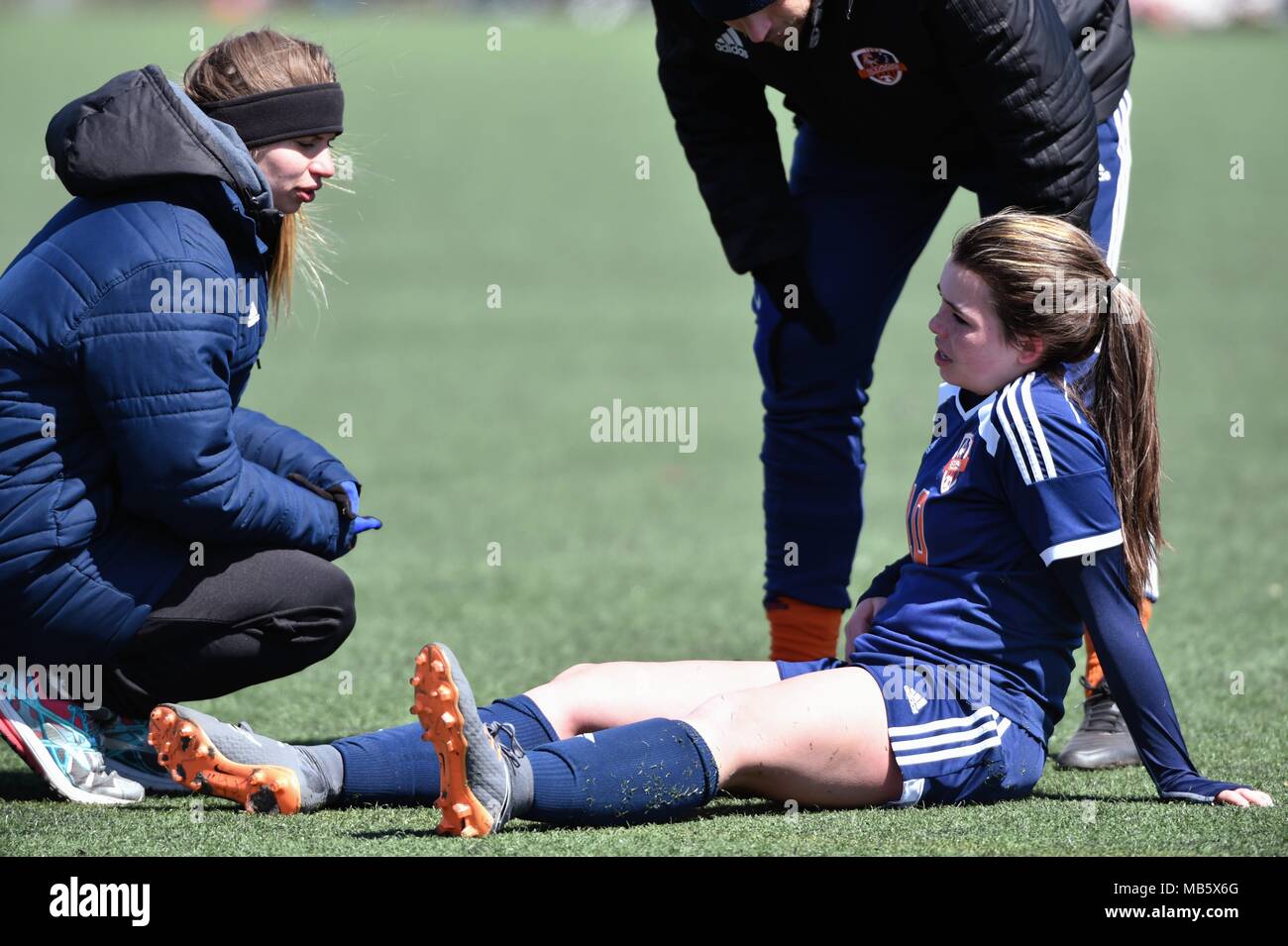 Injured high school player sits upright on the turf while being ...