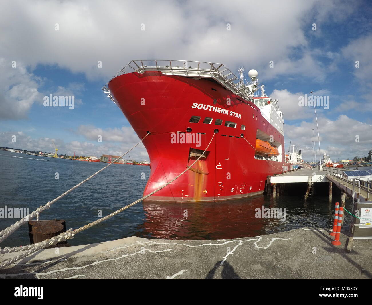 A red dynamic positioning vessel is moored at sea port on a bright day ...