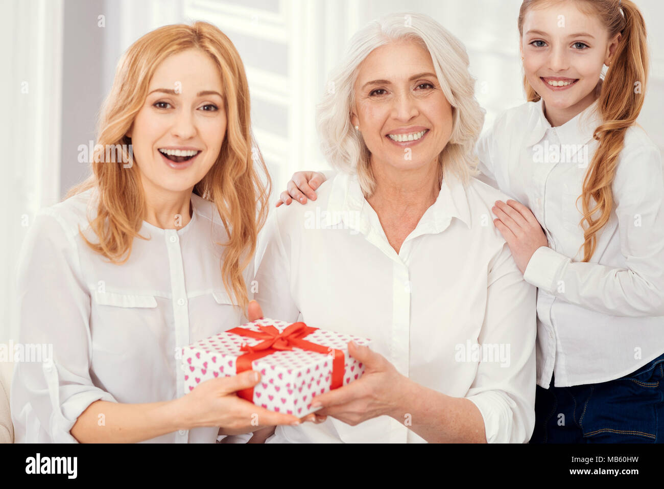 Surprised woman receiving gift from her mom and daughter Stock Photo ...