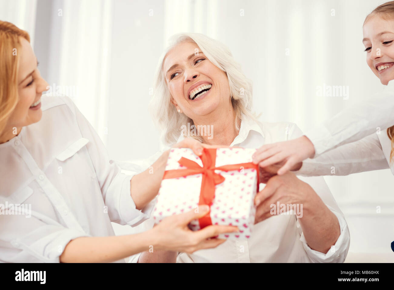 Funny three generations of women joking while sharing present Stock ...