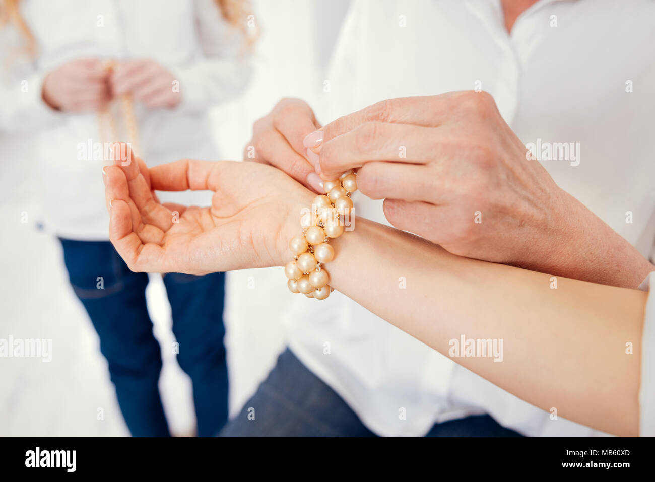 Mindful lady helping daughter to put bracelet on arm Stock Photo - Alamy