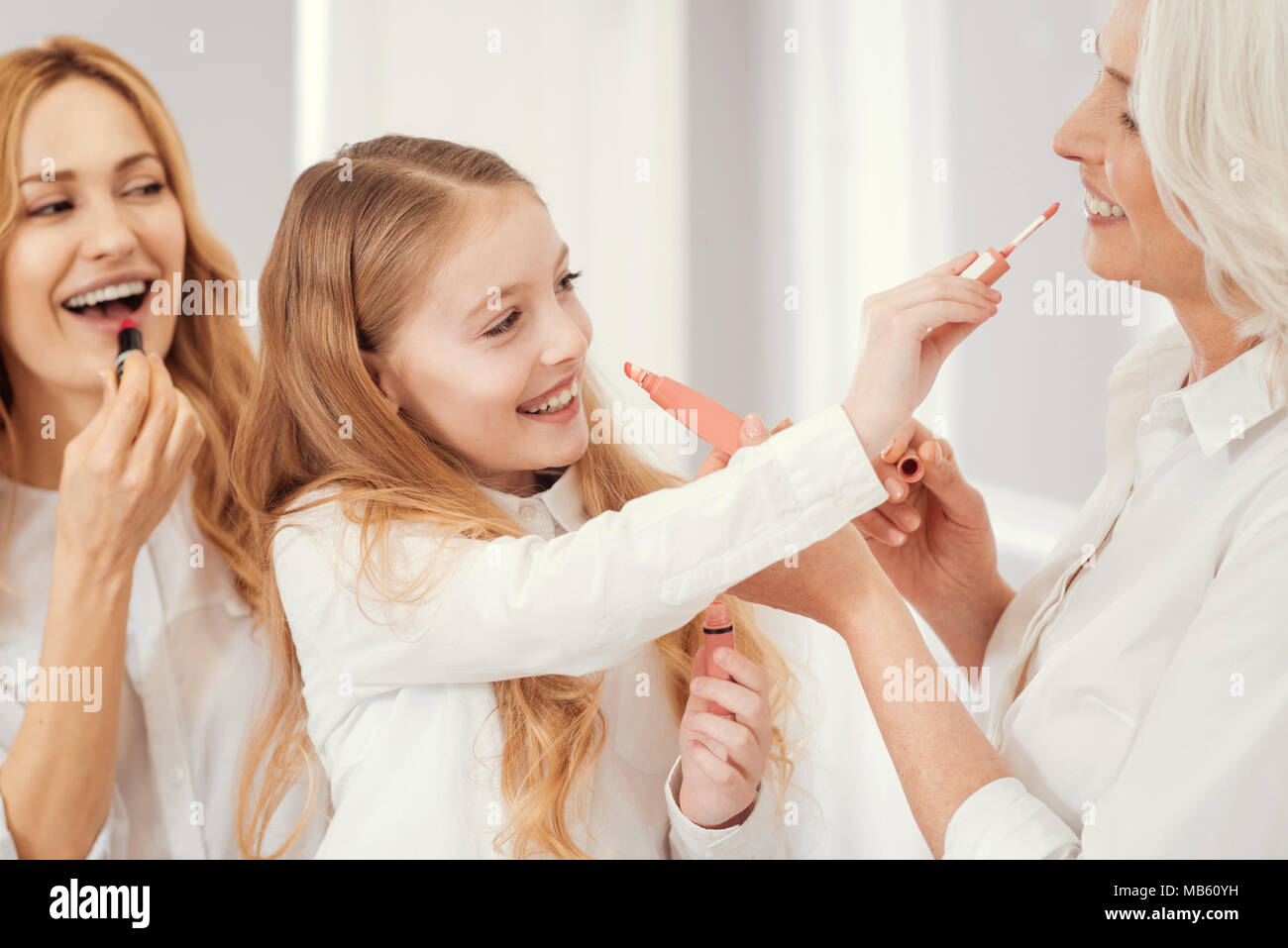 Pretty ladies of different age applying lips makeup together Stock ...