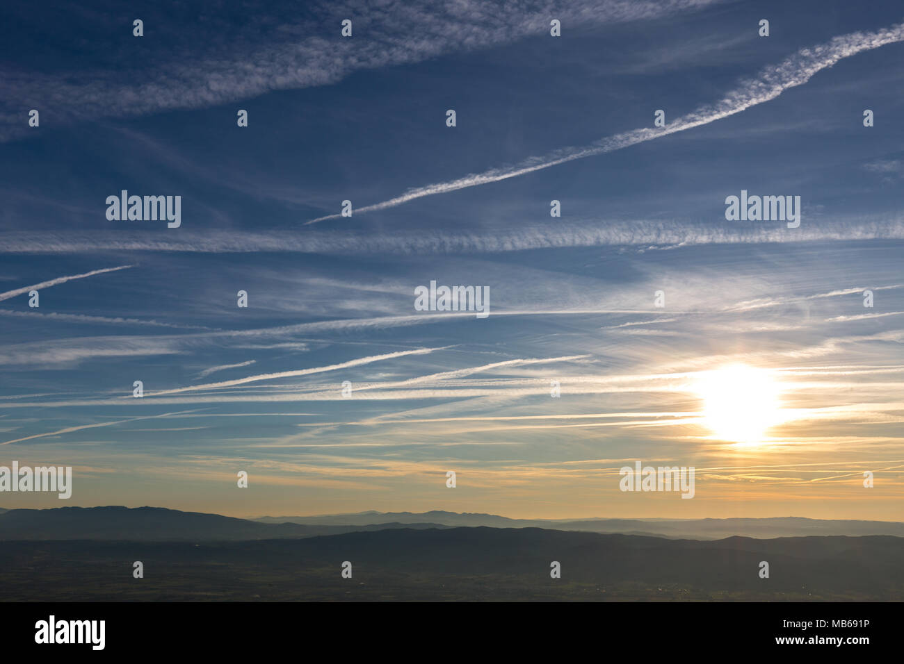 Sunset over distant mountains, with blue sky full of white clouds and ...