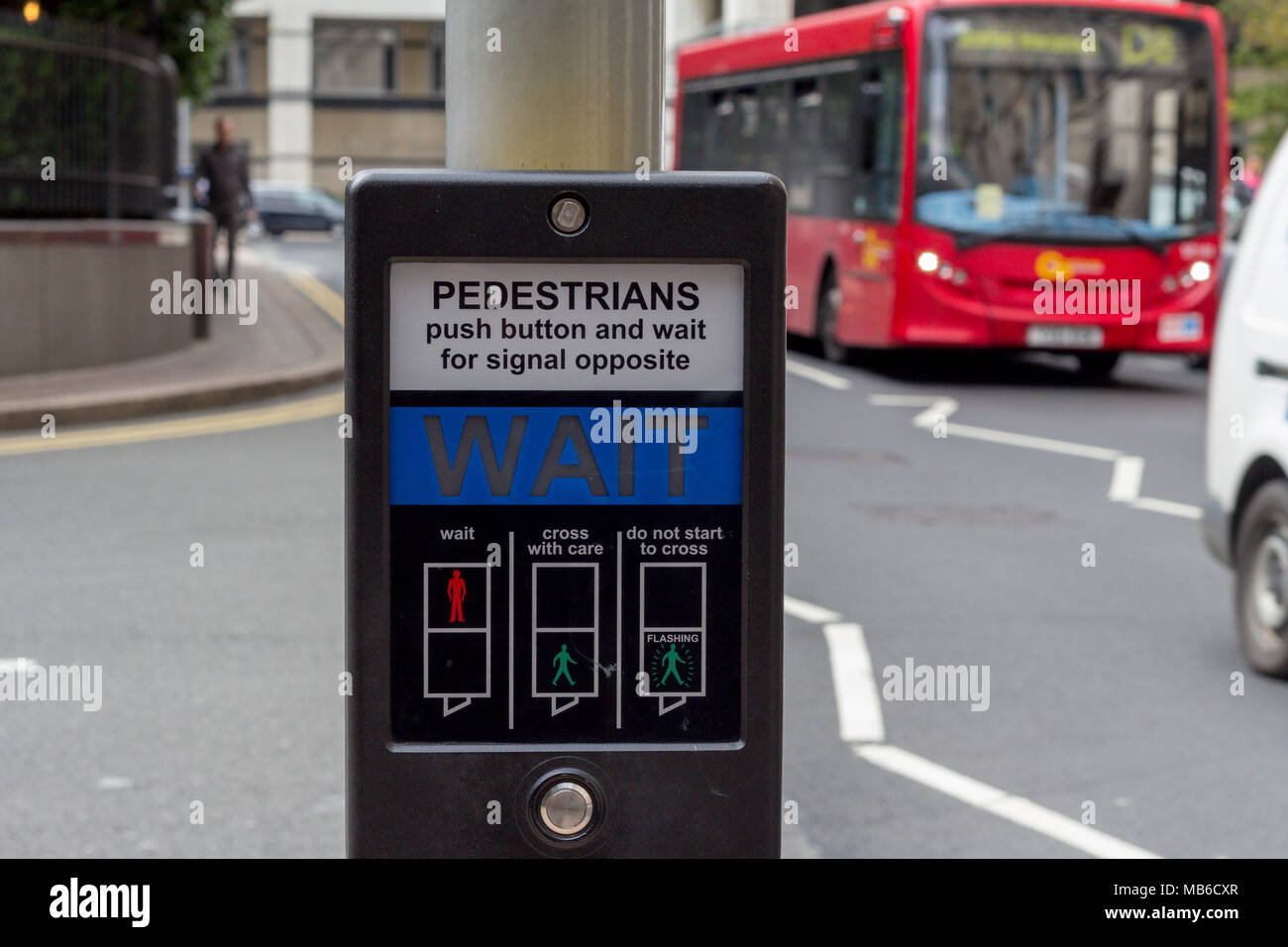 A 'Wait' pedestrian sign at a pedestrian crossing on a busy road in ...