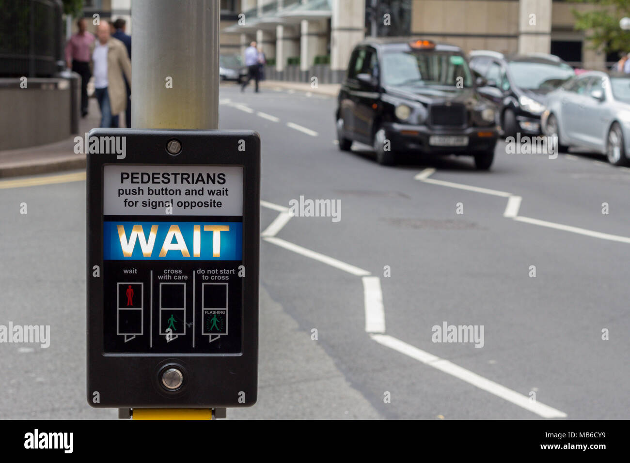 Illuminated 'Wait' pedestrian sign at a pedestrian crossing on a busy ...