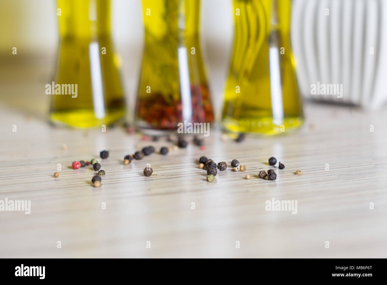 Colorful pepper seeds on the kitchen table and three bottes of olive ...