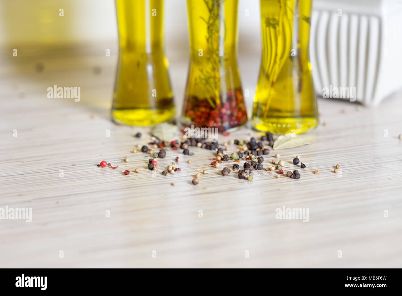 Colorful pepper seeds on the kitchen table and three bottes of olive ...