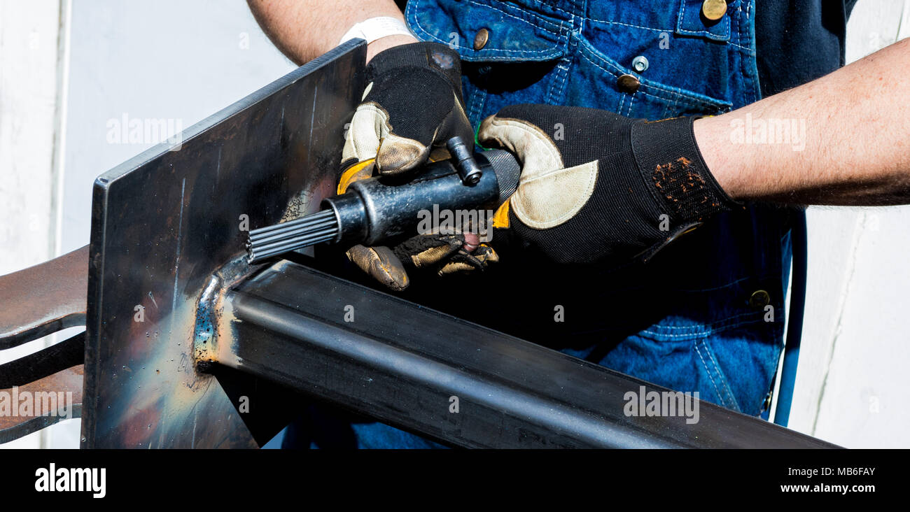 Welding steel worker breaking away slag from a perfect spiral weld bead ...