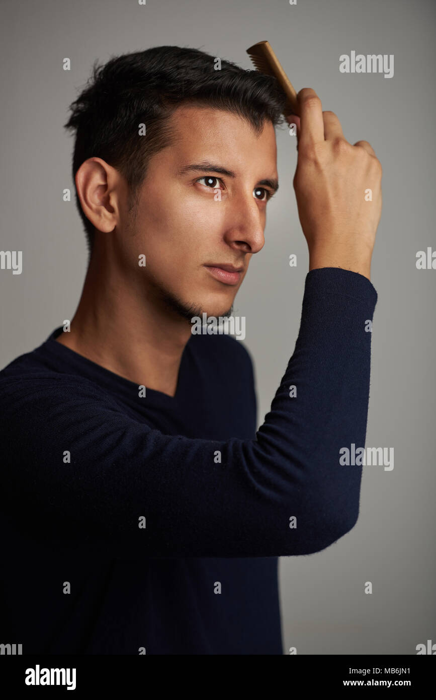 Young man grooming his hairwith brush on grey background Stock Photo ...