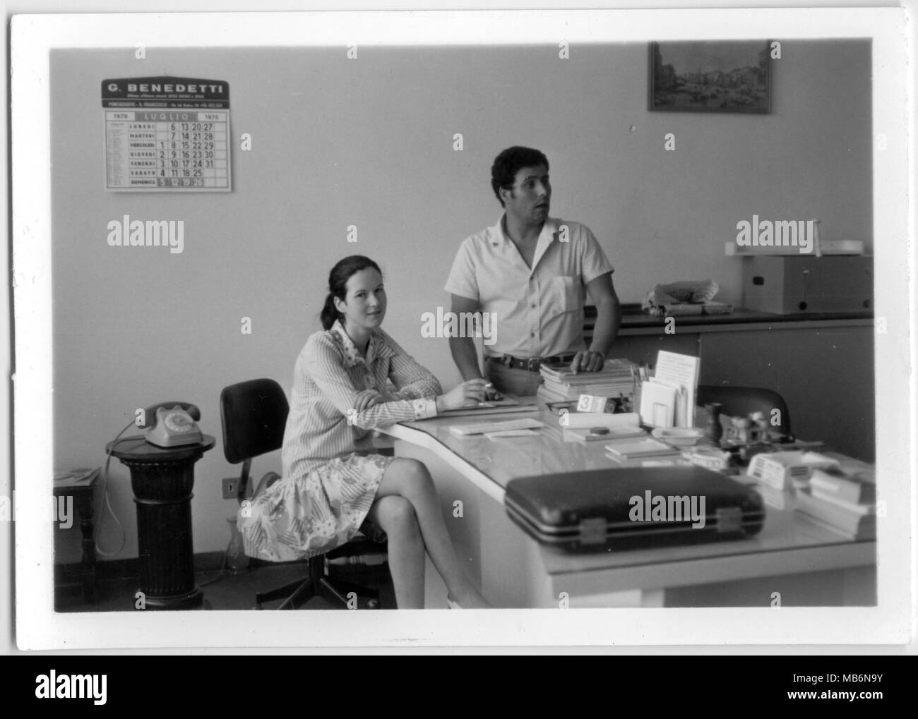 Young secretary with her boss smoking cigarette at a desk. 60s 1970s ...