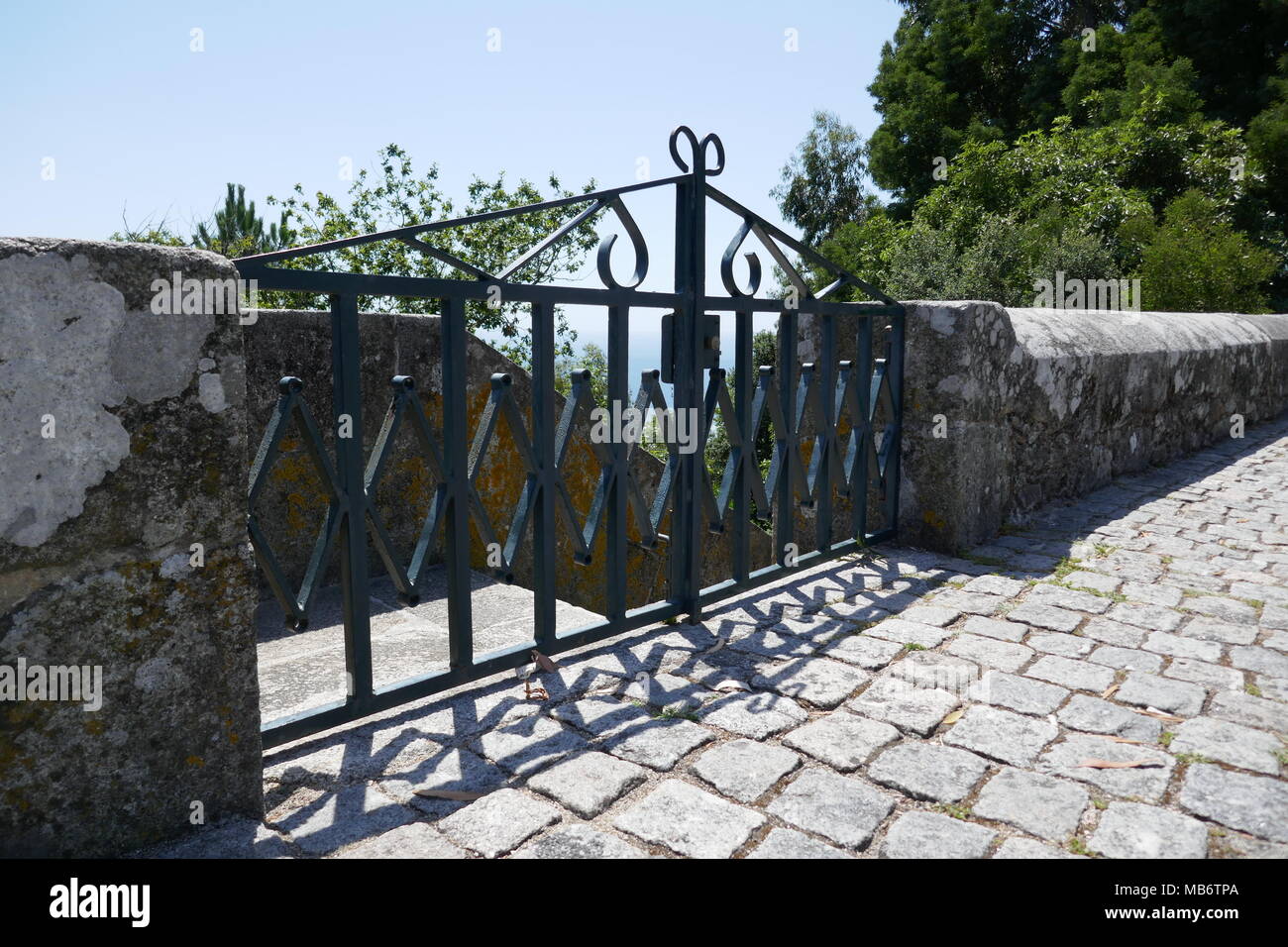 Steel gate and concrete wall alongside a cobblestone street Stock Photo ...