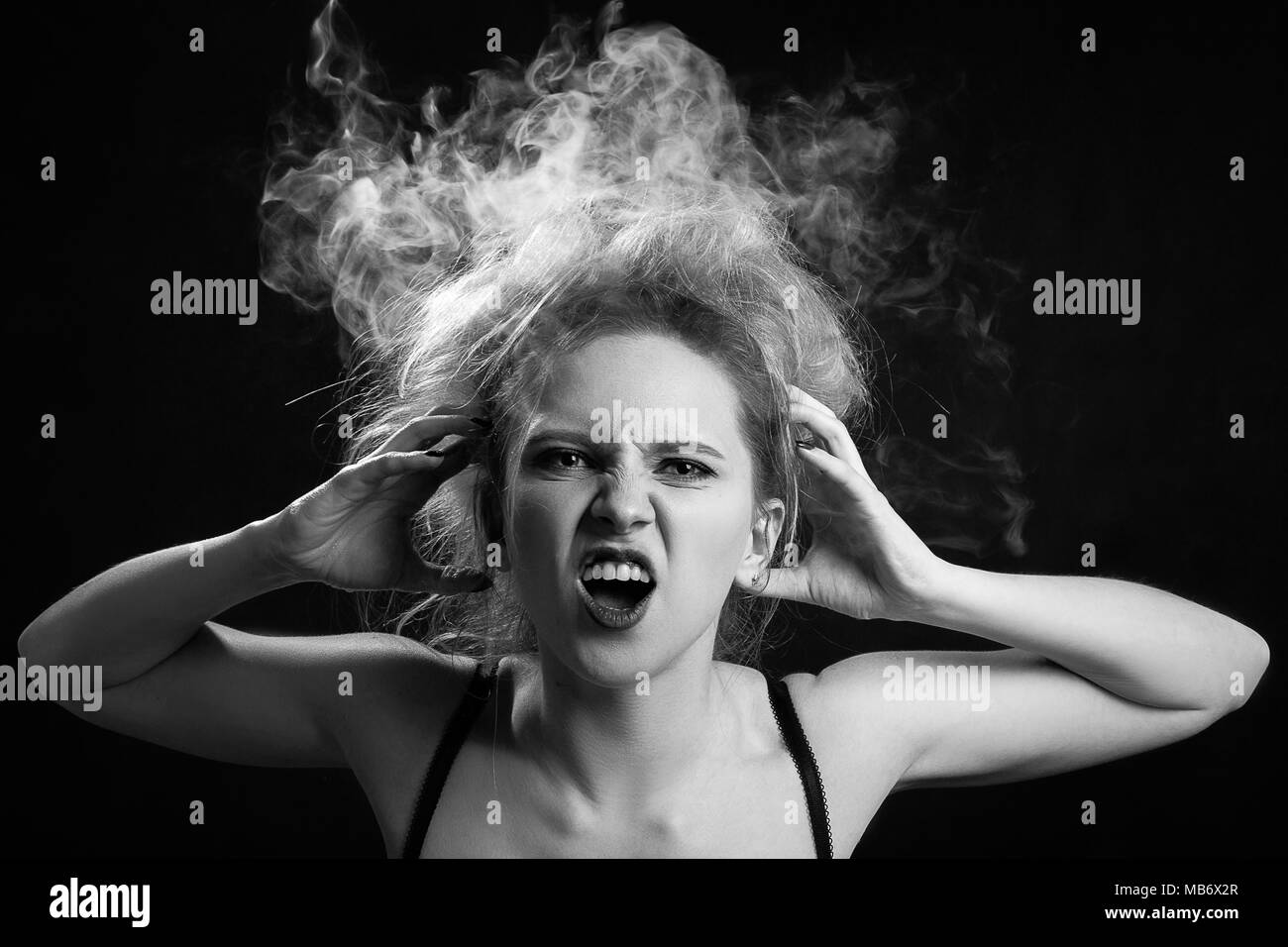 stressed woman with cloud of smoke on her head on black background ...