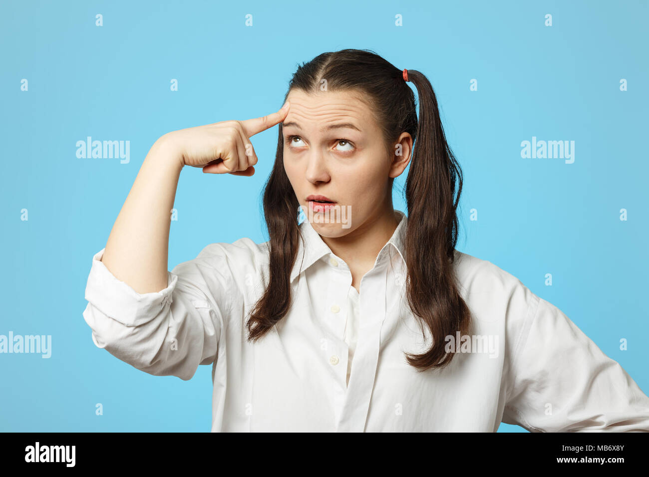 sly girl thinker on blue background with finger oh her head Stock Photo ...