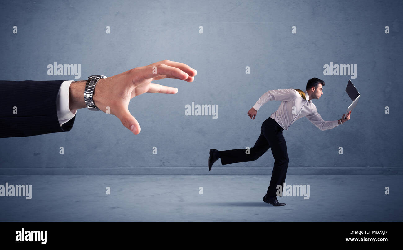 Young miniature businessman running from a big hand with blueish ...