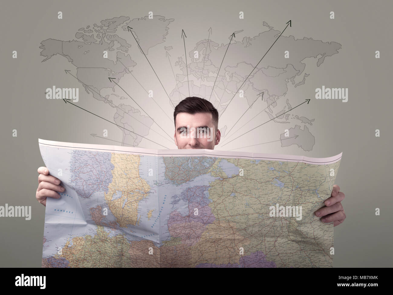 Handsome young man holding a map with world map and arrows behind him ...