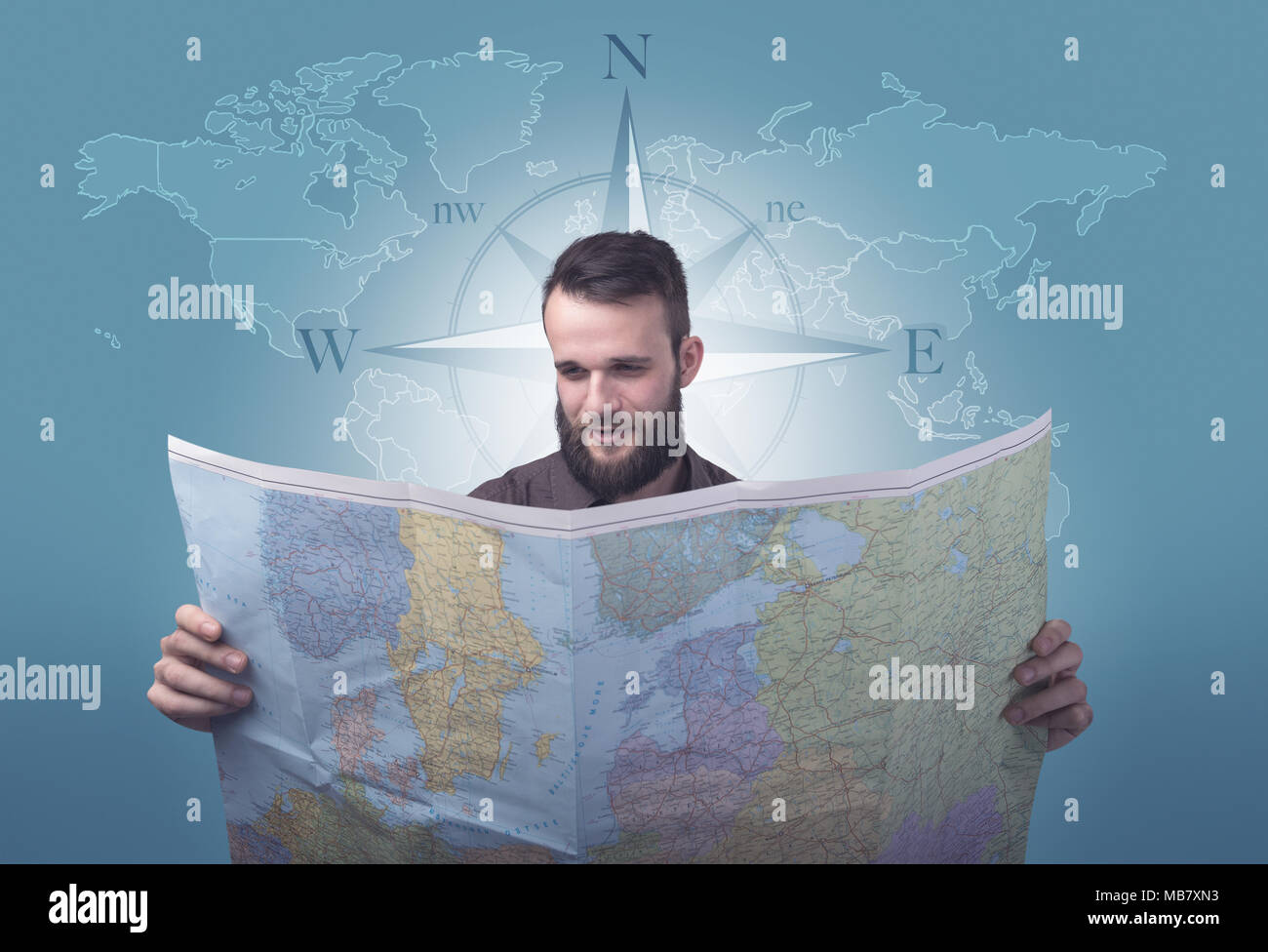 Handsome young man holding a map with a world map and a compass behind ...