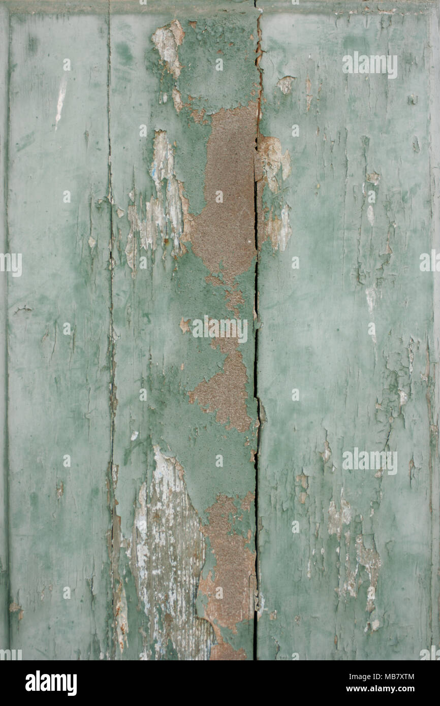 A detail showing faded green, peeling paintwork on a door in Matera ...