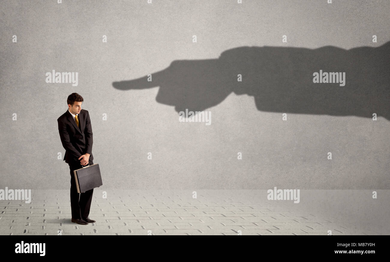 Business person looking at huge shadow hand pointing at him concept on ...