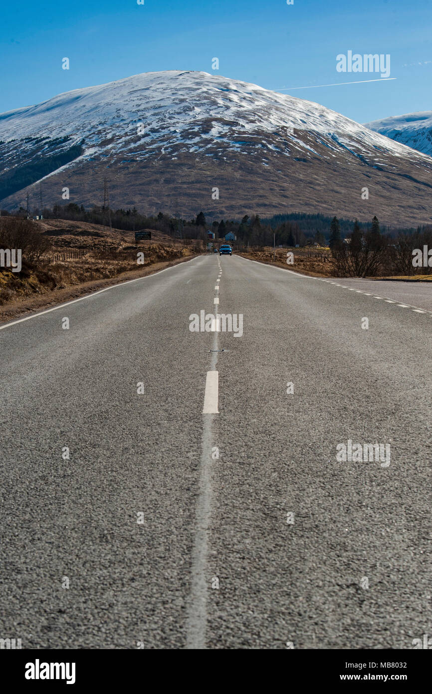 A deserted, empty road in the Scottish Highlands with snow capped ...