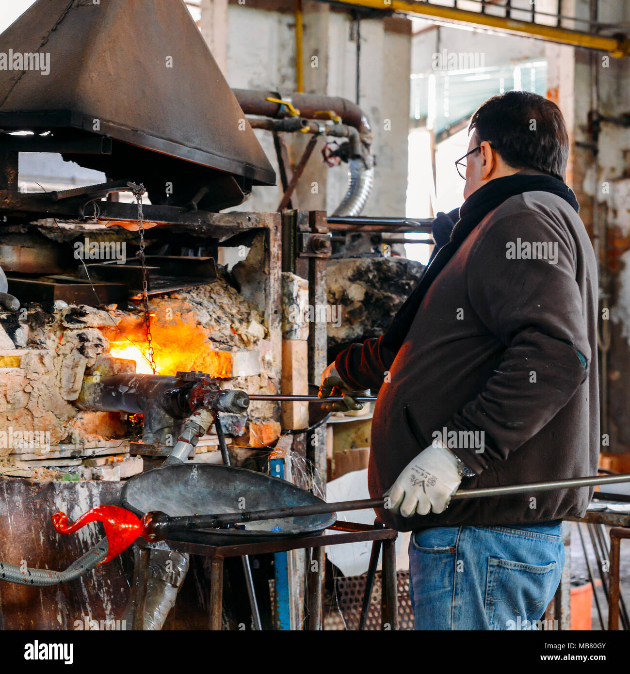 Traditional glass blower forming a beautiful piece of glass in a ...