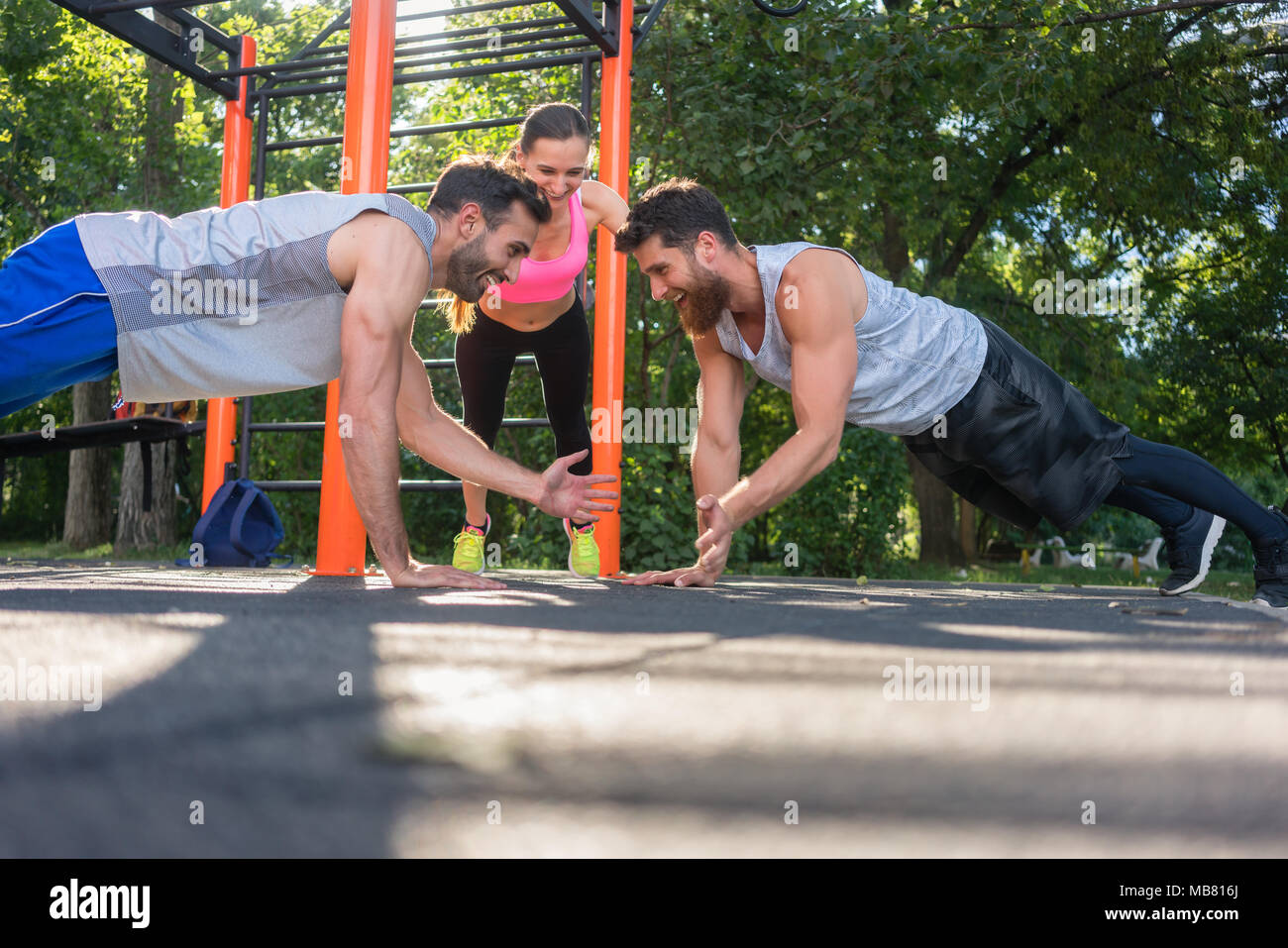 Two young men clapping hands from plank position during partner workout ...