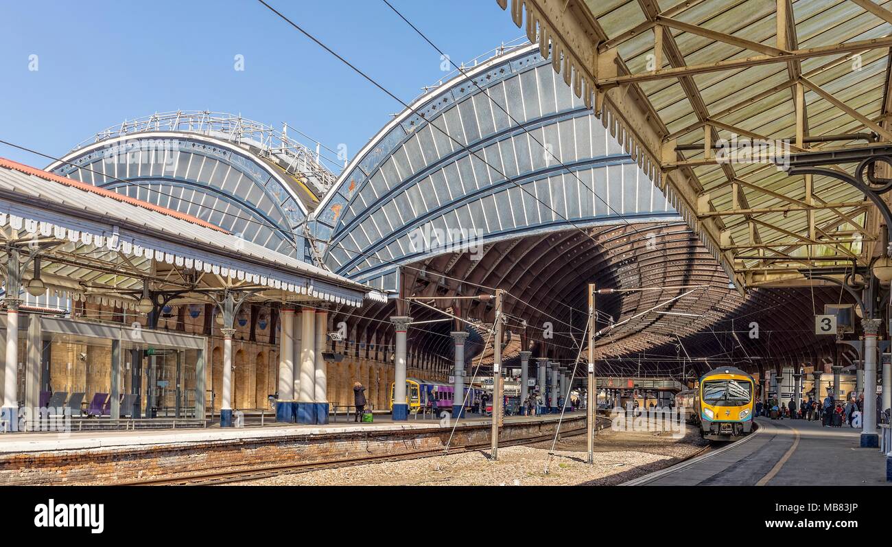 Train waits at the railway platform underneath an ornate curved roof ...