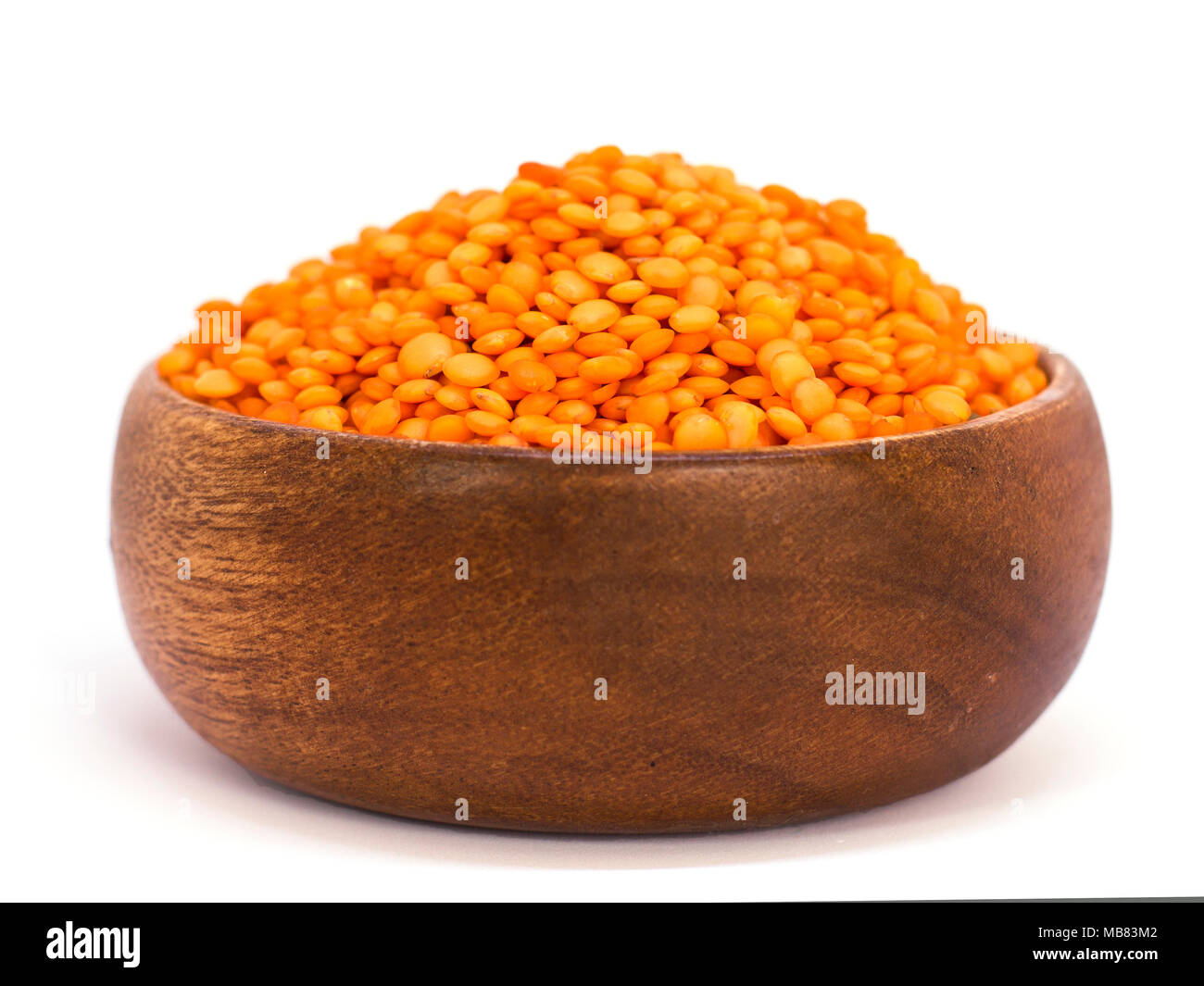 Red raw lentils in a wooden bowl. Isolated on the white background ...