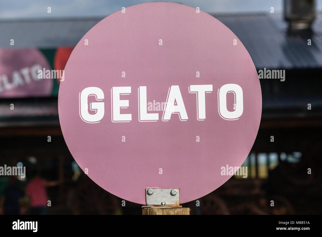 Gelato word white letters on maroon round disk sign board outside food ...