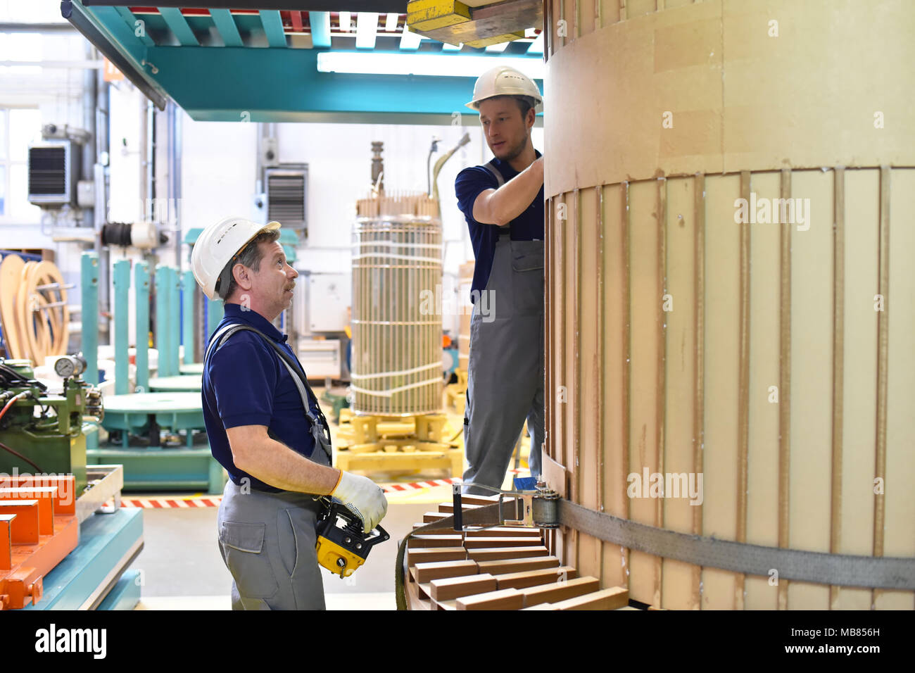 group worker assembles a transformer in mechanical engineering ...