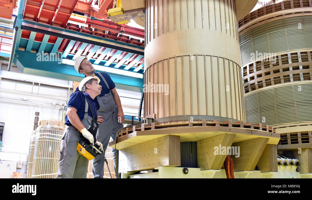 group worker assembles a transformer in mechanical engineering ...