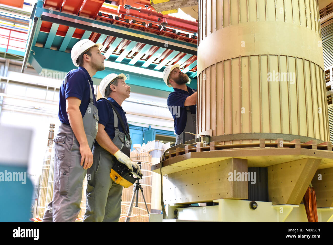 group worker assembles a transformer in mechanical engineering ...