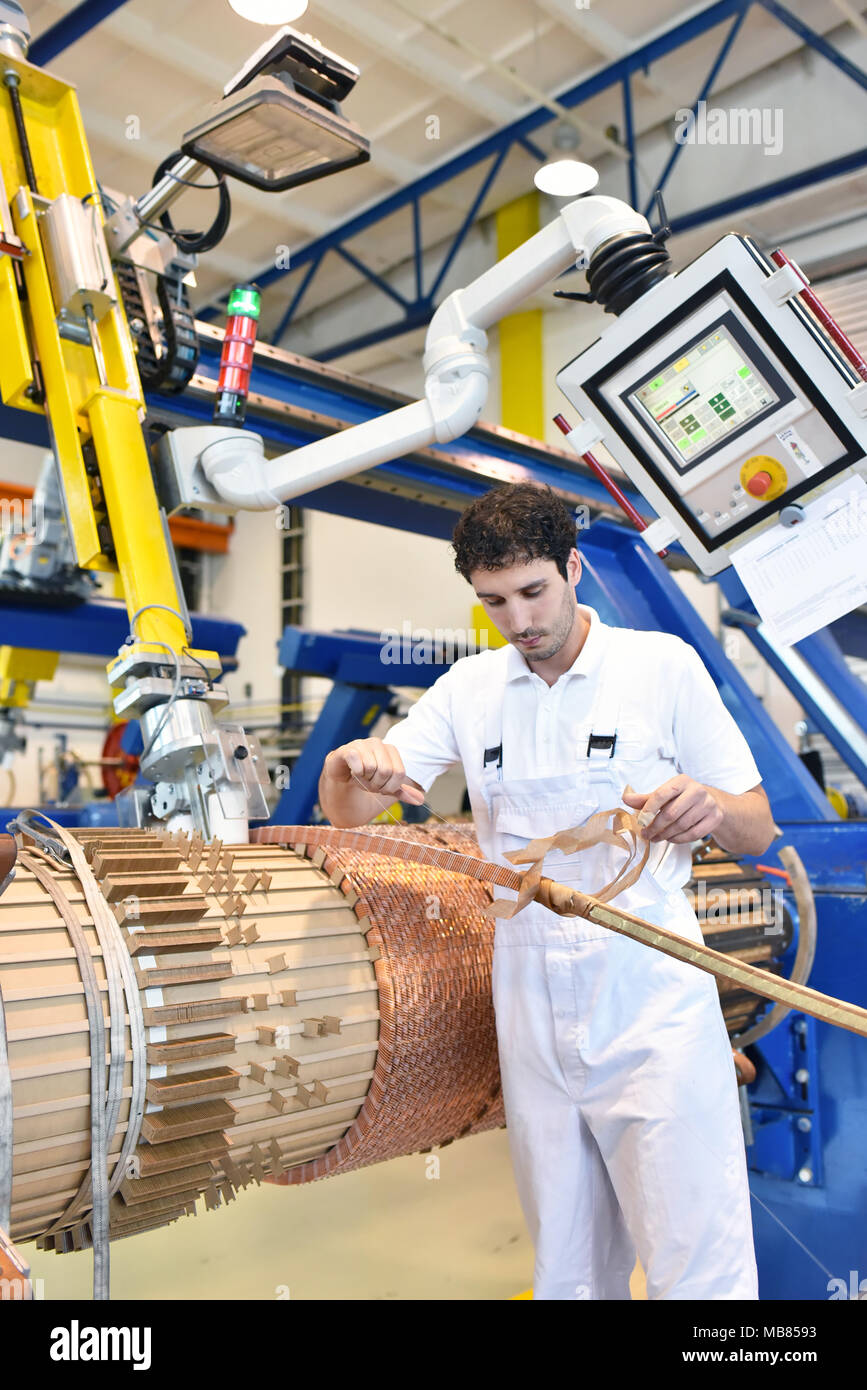 young mechanical engineering workers operate a machine for winding ...