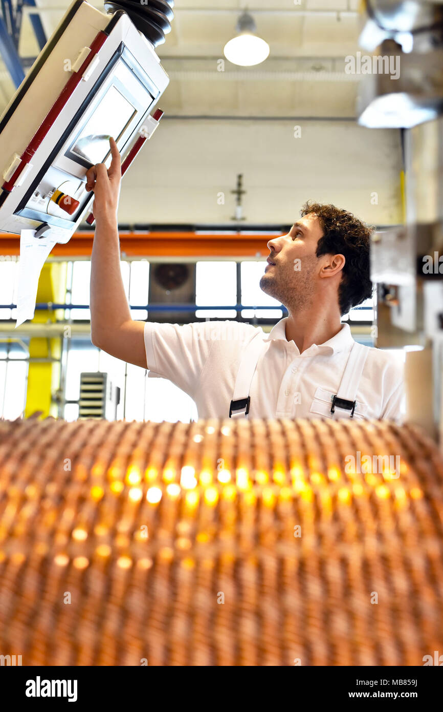 young mechanical engineering workers operate a machine for winding ...