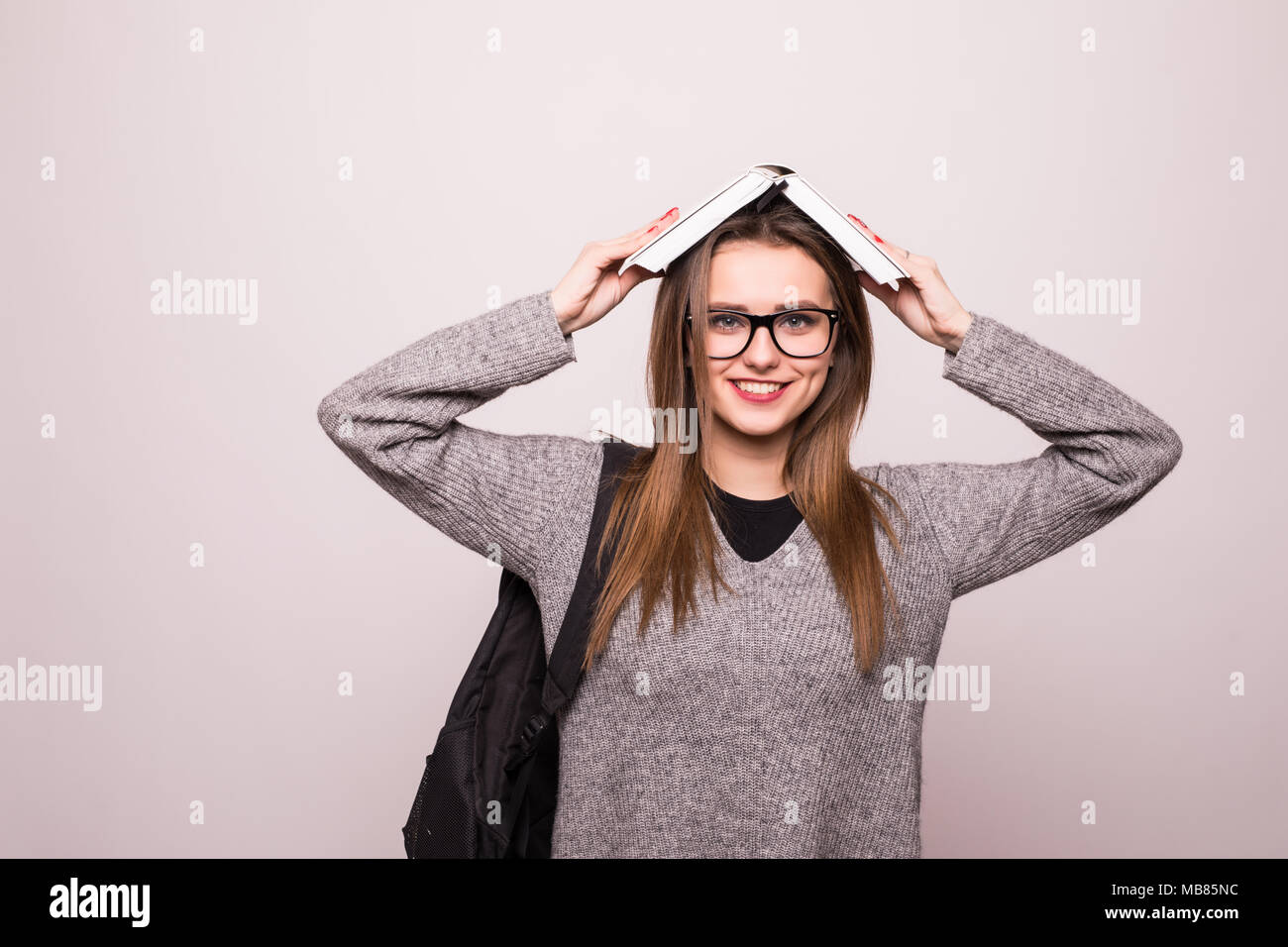Female student, holding book on head. Isolated on white background ...