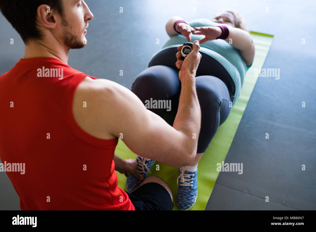Coach Timing Obese Woman in Health Club Stock Photo - Alamy
