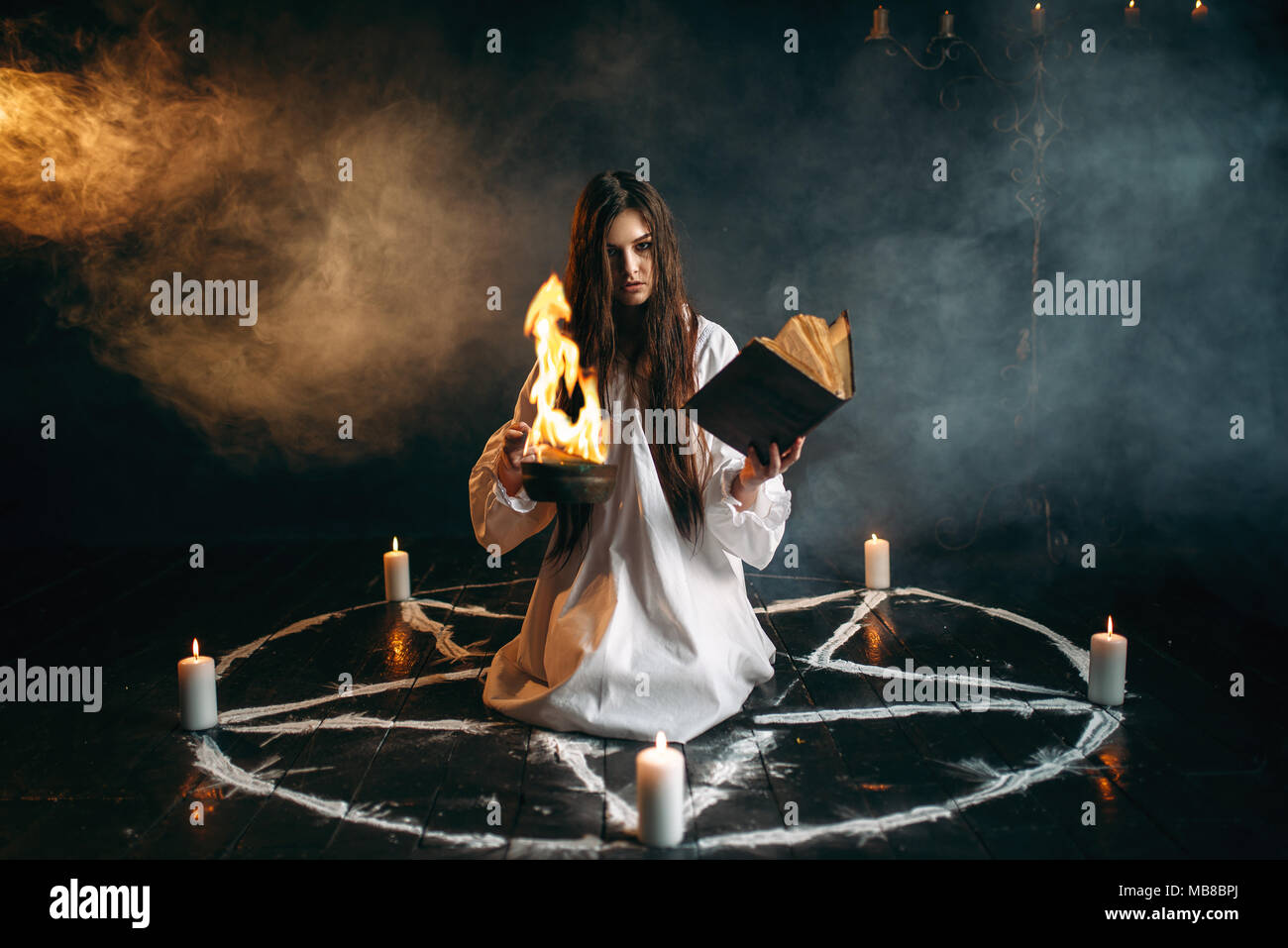 Witch in white shirt sitting in the center of pentagram circle with ...