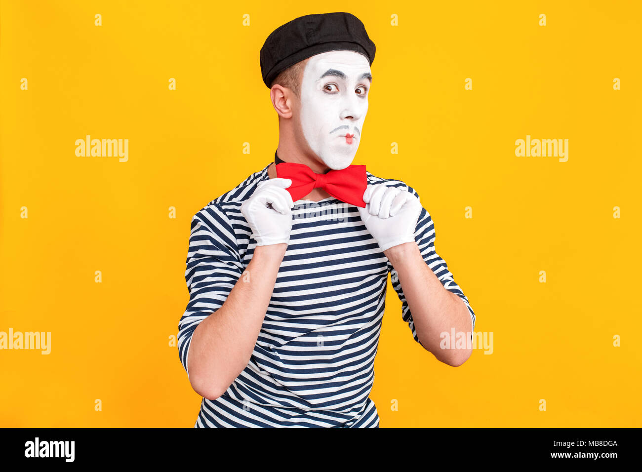 Mime man holding bow of tie and looking at camera. Emotions and ...