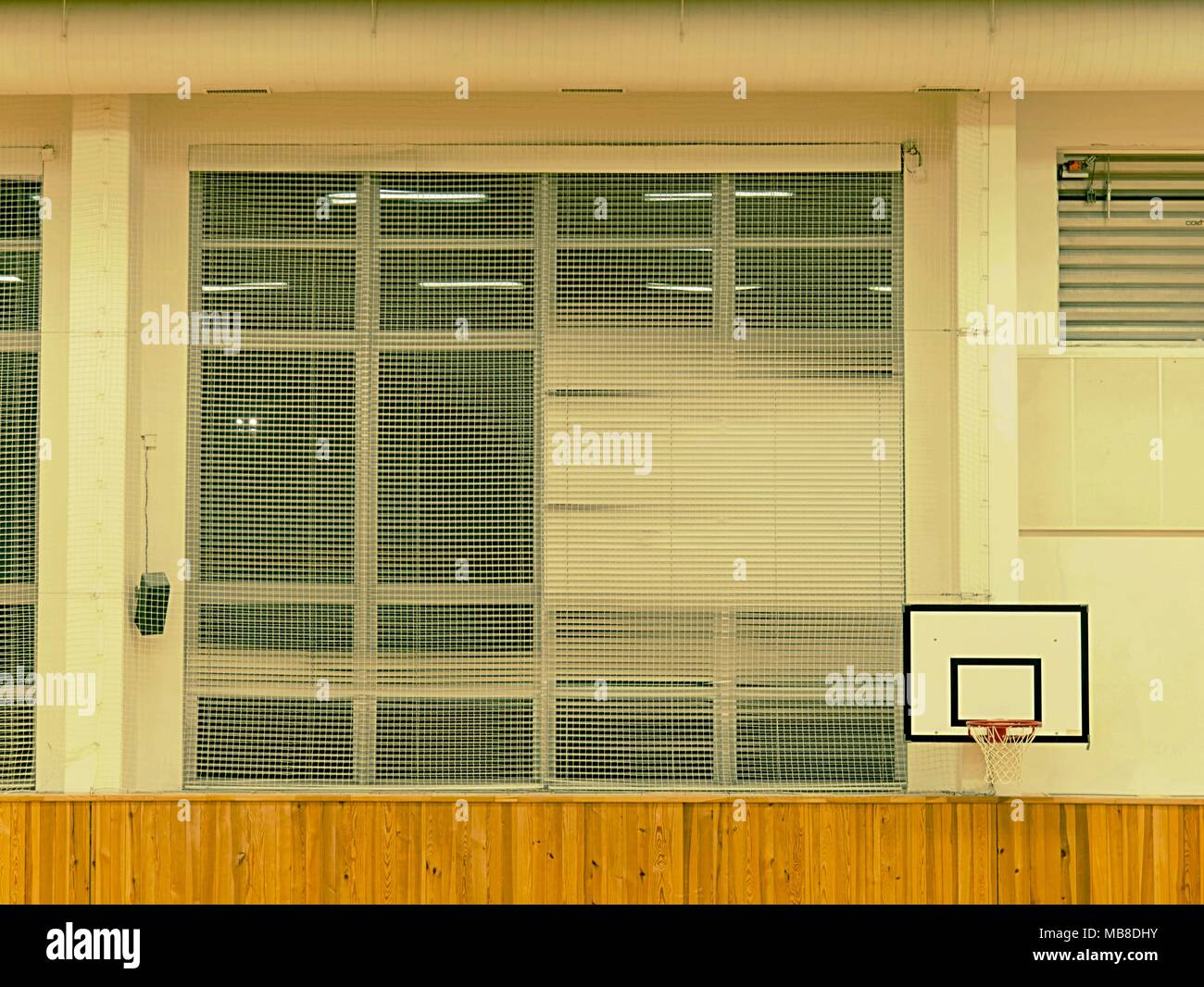 Interior of school gym with basketball board and basket. Safety nets ...