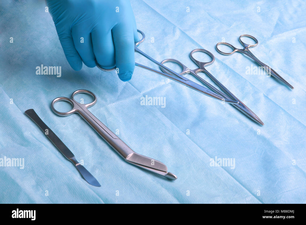 Detail shot of sterilized surgery instruments with a hand grabbing a ...