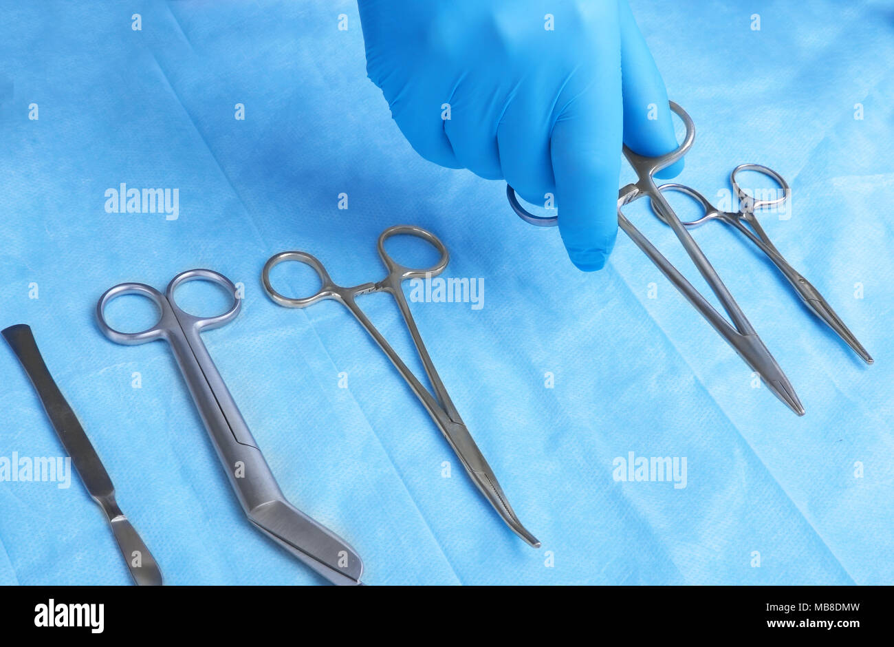 Detail shot of sterilized surgery instruments with a hand grabbing a ...