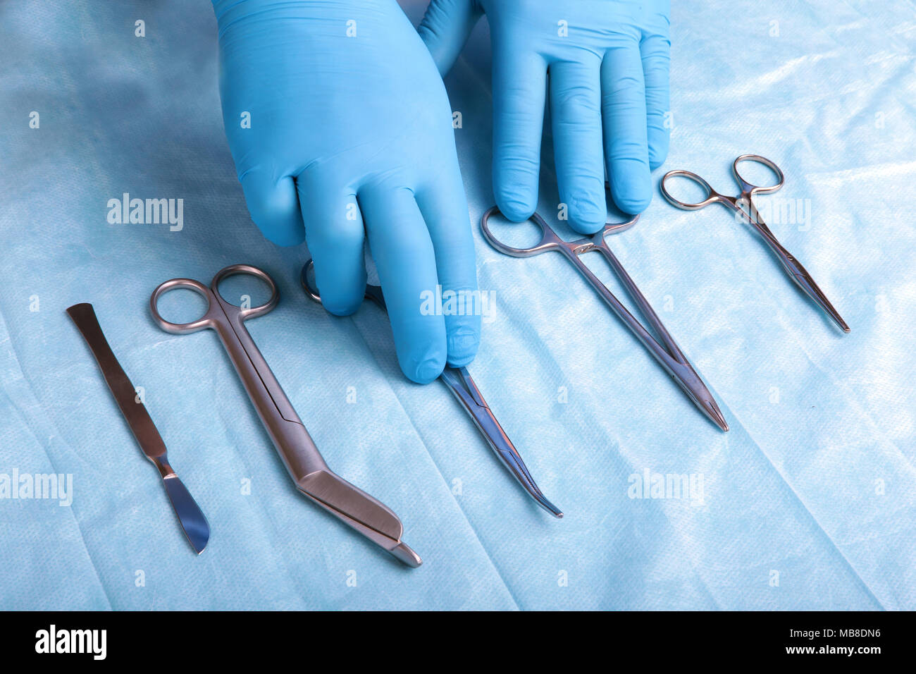 Detail shot of sterilized surgery instruments with a hand grabbing a ...